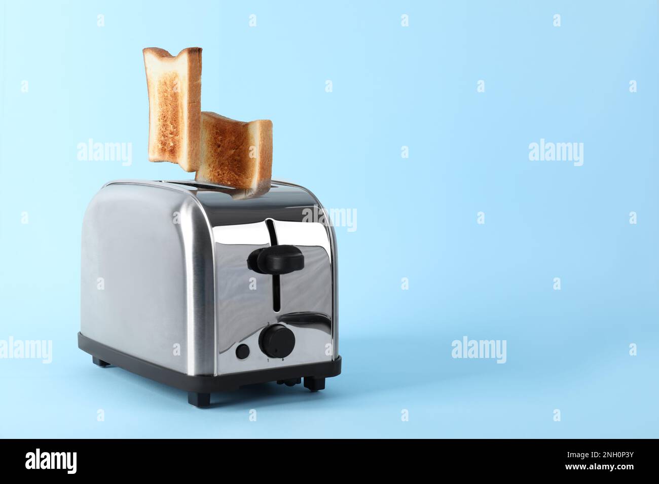 Bread slices popping up from modern toaster on light blue background ...