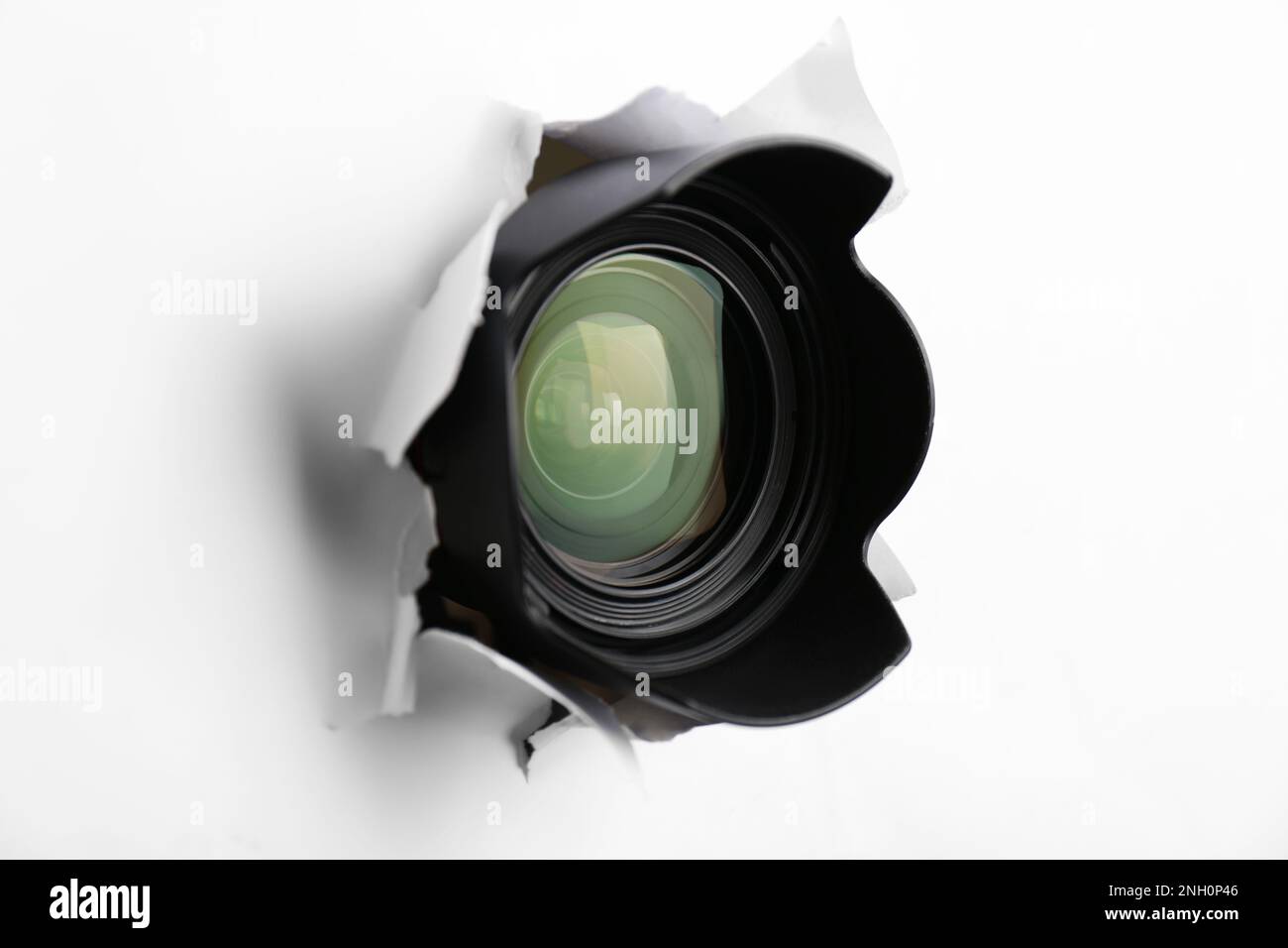 Hidden camera lens through torn hole in white paper Stock Photo - Alamy