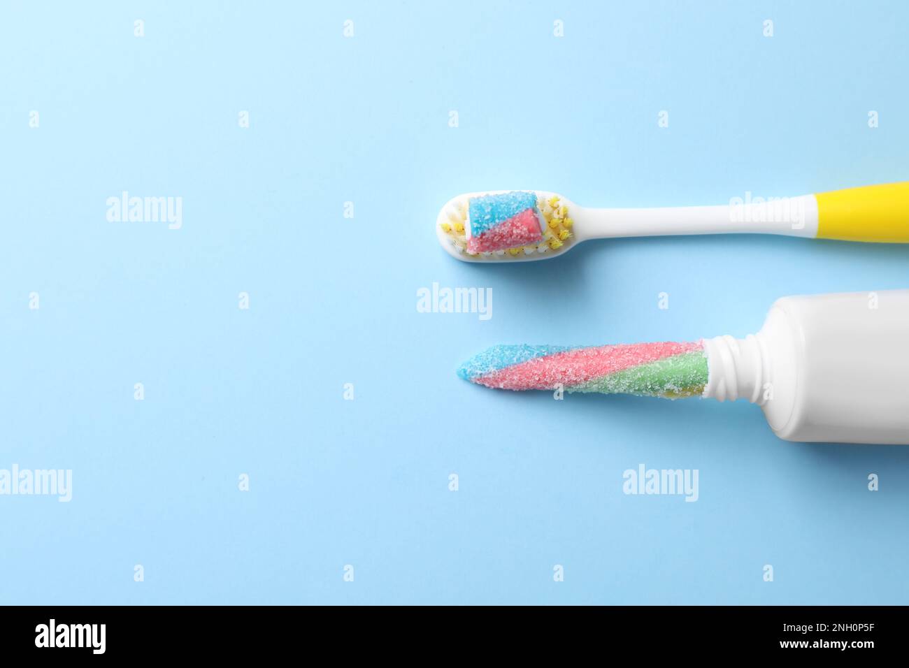 Toothpaste tube and brush with gummy candies on light blue background ...
