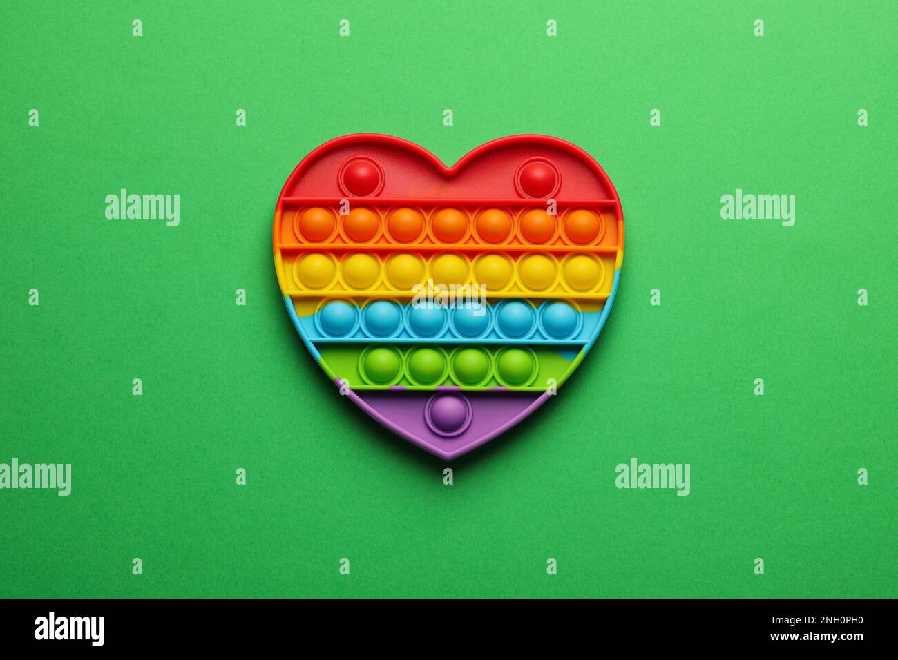 Heart shaped rainbow pop it fidget toy on green background, top view ...