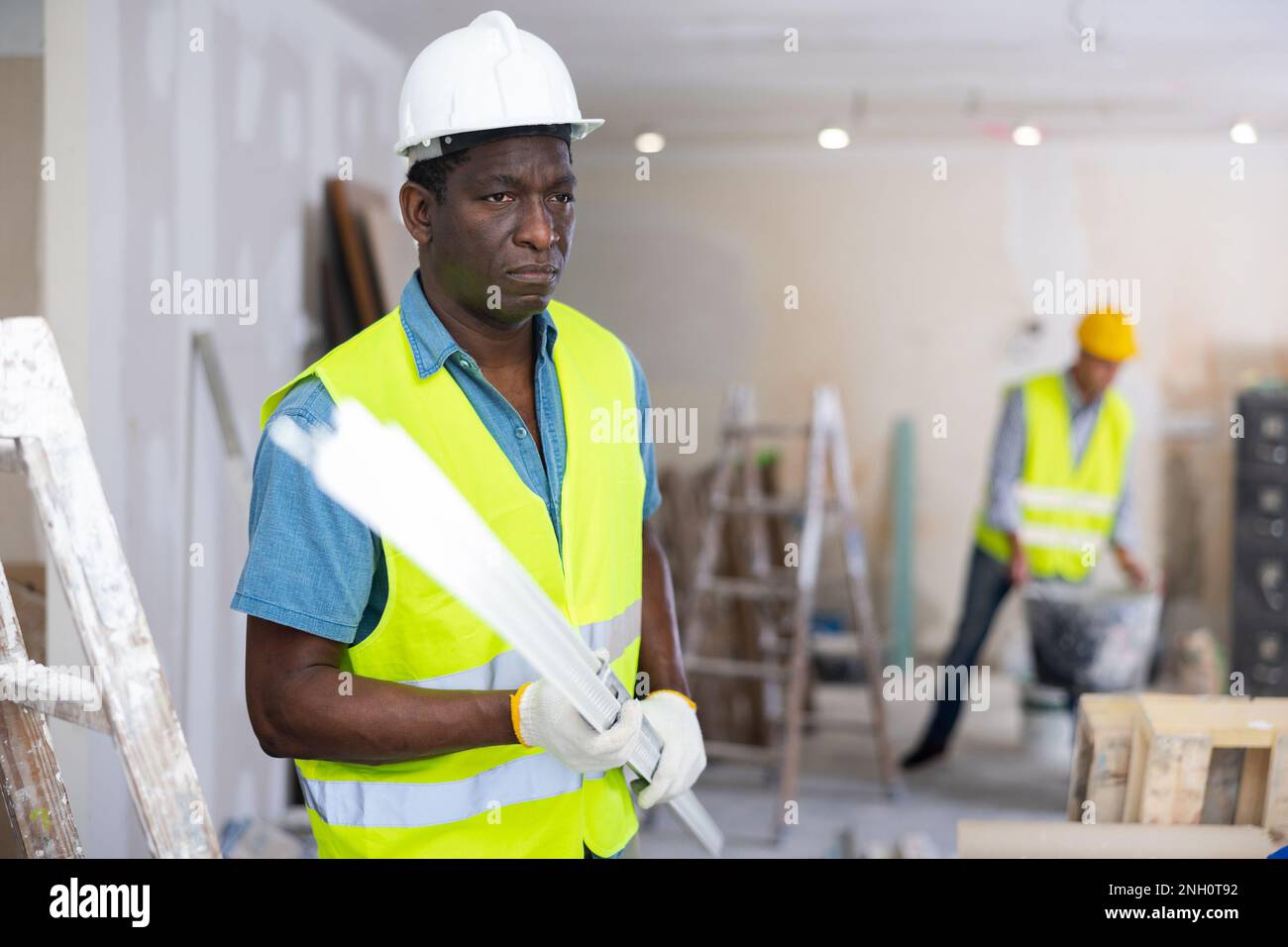 African-american man builder carrying metallic profile while working in ...