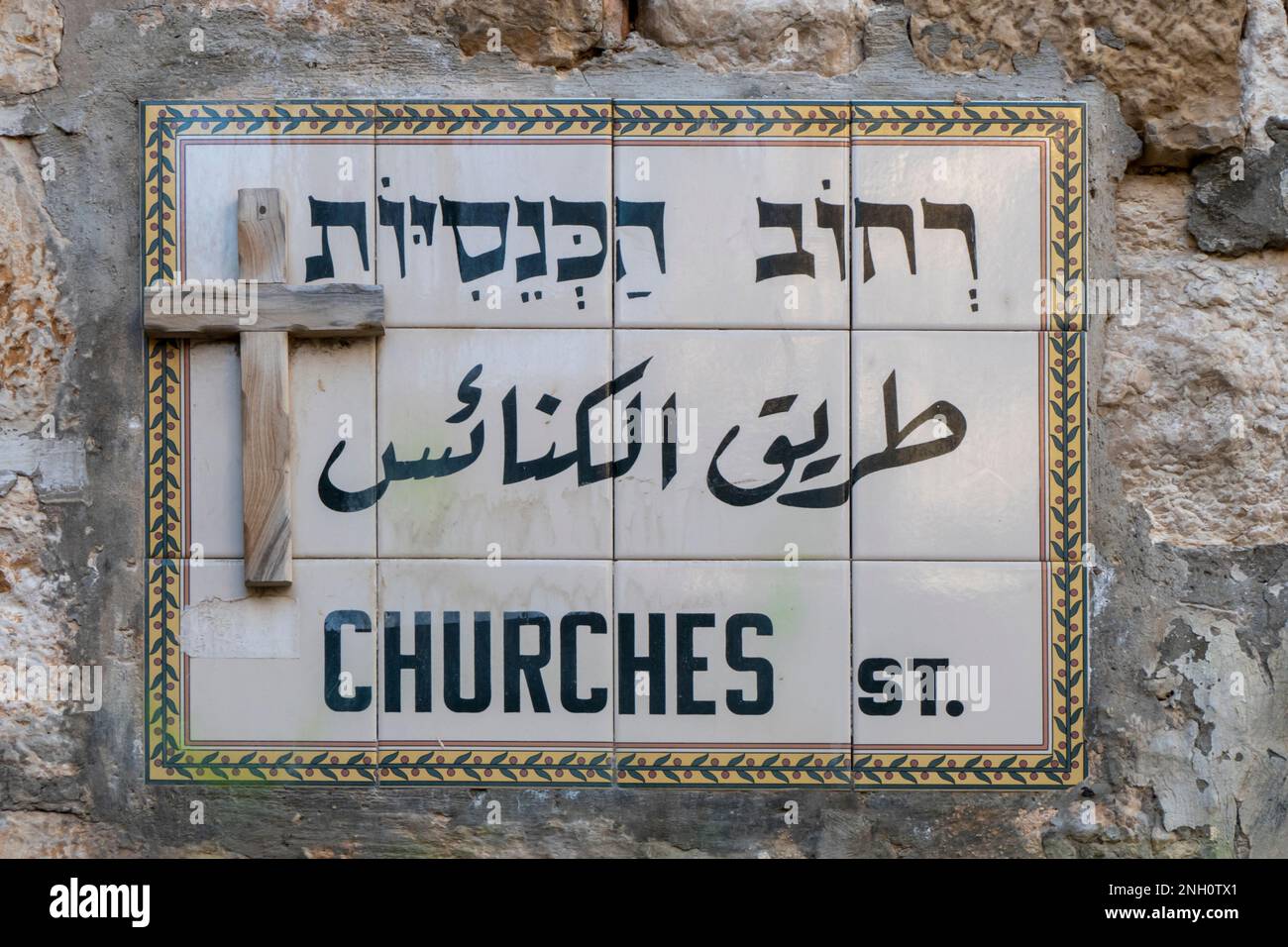 A wooden cross displayed over a glazed ceramic street sign in English ...