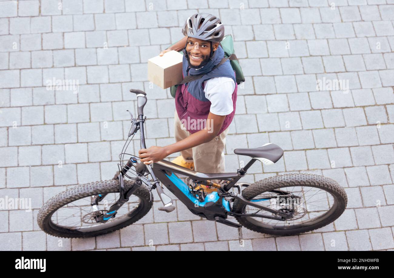 Black man, delivery bike and street portrait from top view for ...