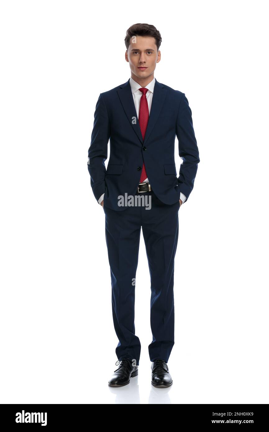 handsome businessman putting his hands in pockets, wearing a suit and ...