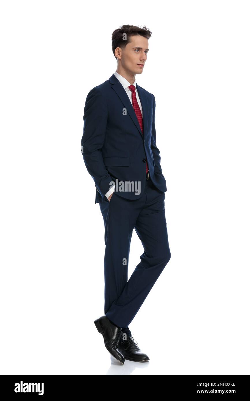 elegant businessman with hands in pockets crossing his legs, wearing a ...