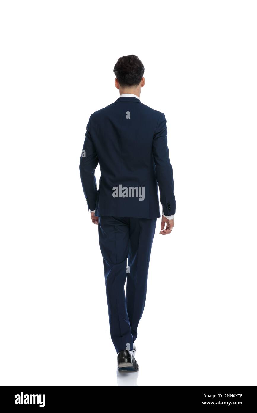 elegant businessman walking away from the camera, wearing a suit and ...