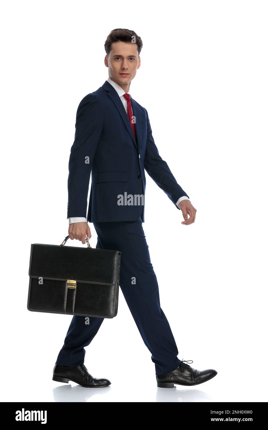 handsome businessman walking and holding a briefcase to the side ...