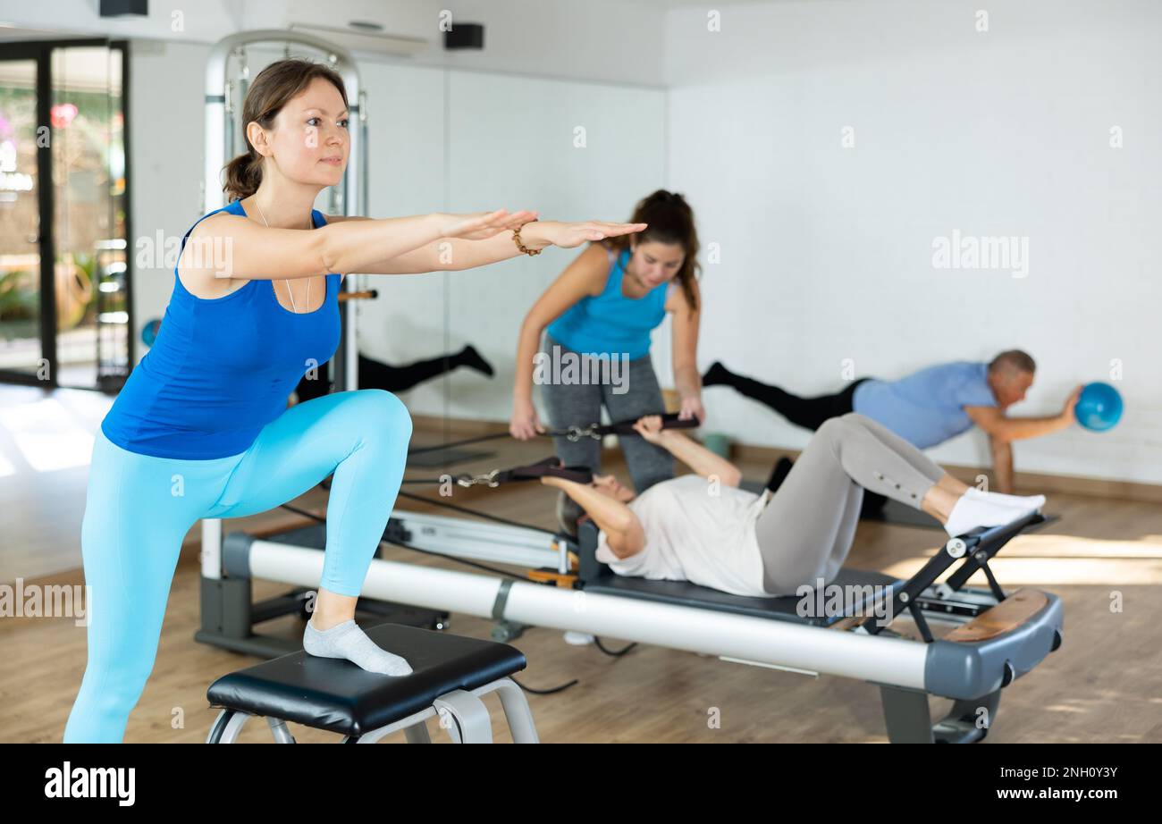 Positive middle-aged woman performing stretching exercises while using ...