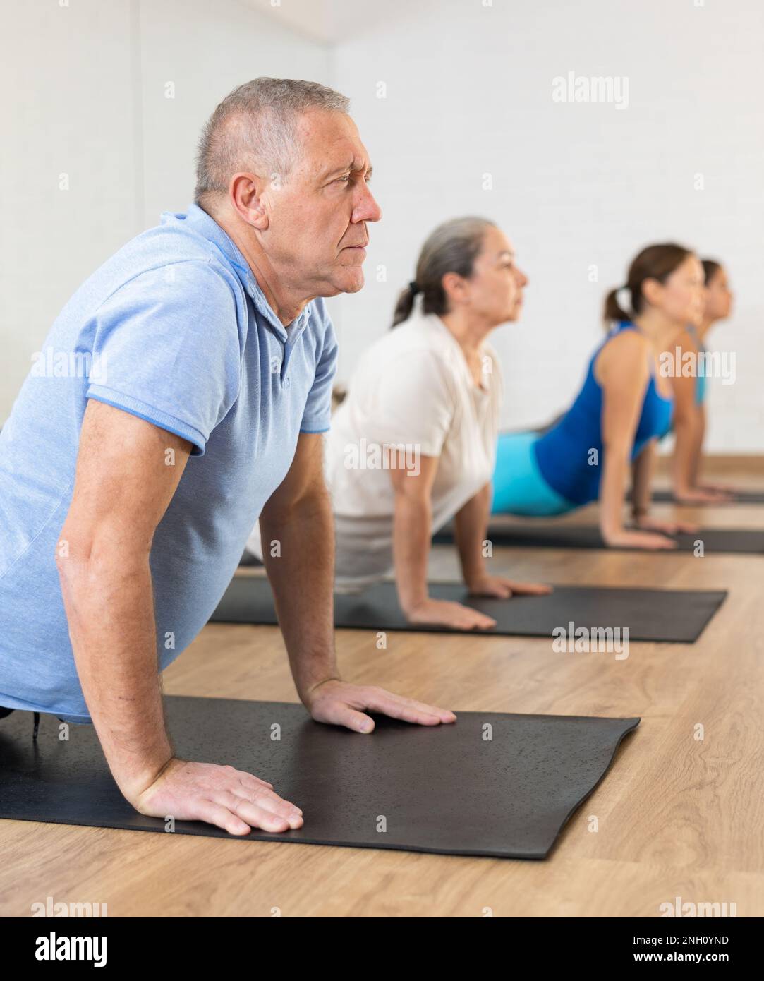 Class of male and women of different ages in active wear doing cobra ...