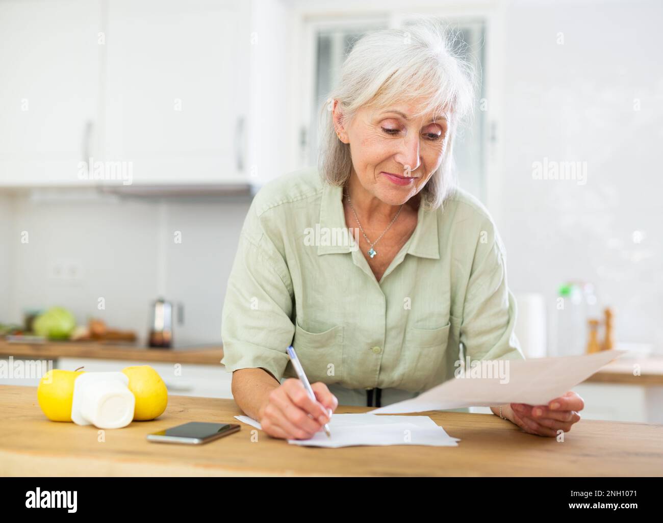 Positive old woman calculating bill payment Stock Photo - Alamy