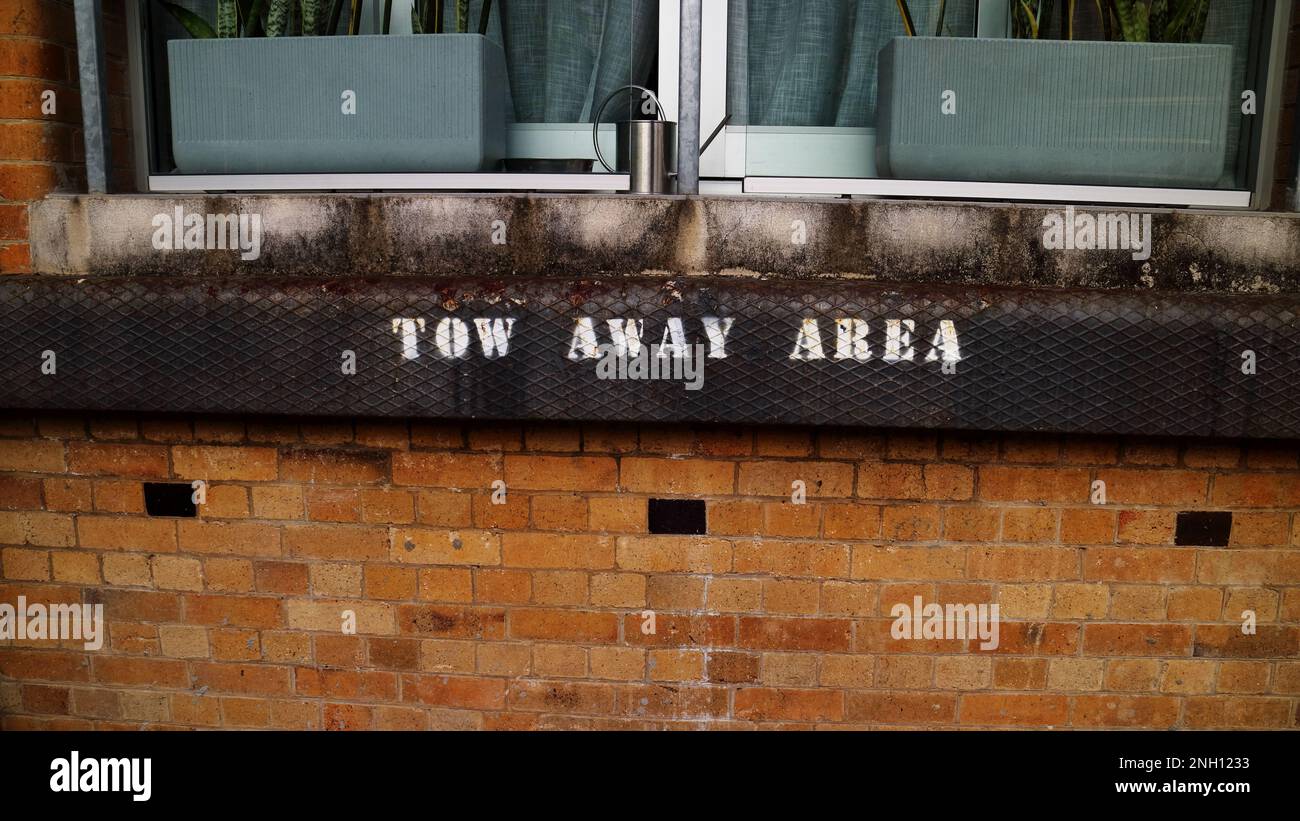 Tow away area sign painted on a wall of apartment building Stock Photo ...