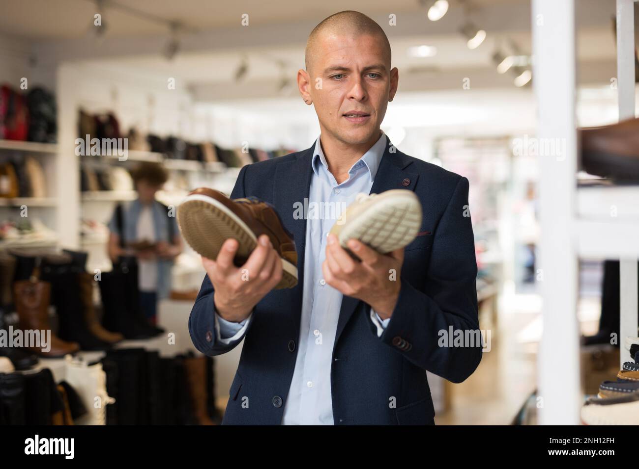 Male shopper comparing two moccasins models in shoe store Stock Photo ...