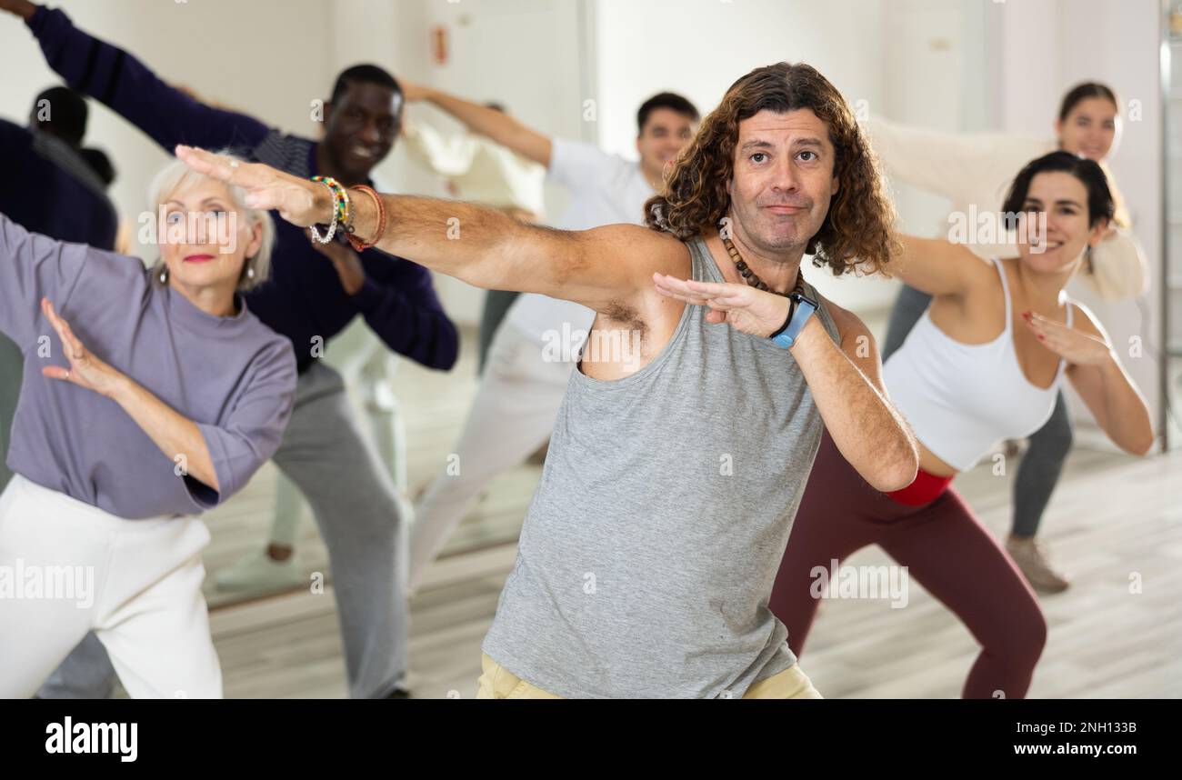 Positive man practicing vigorous dance movements during group class ...