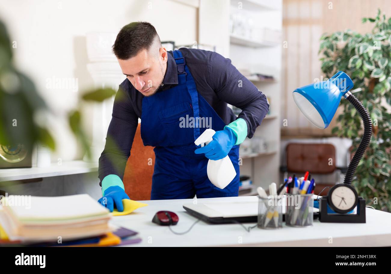 Man wipes dust from table in modern office Stock Photo - Alamy