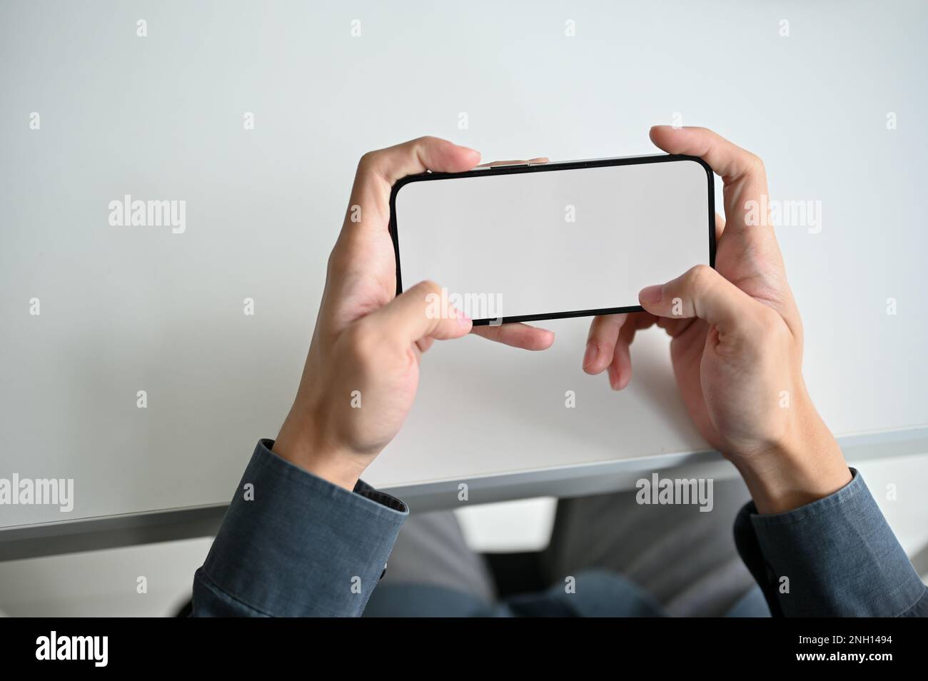 Top view of a man playing mobile game at the table, holding a ...