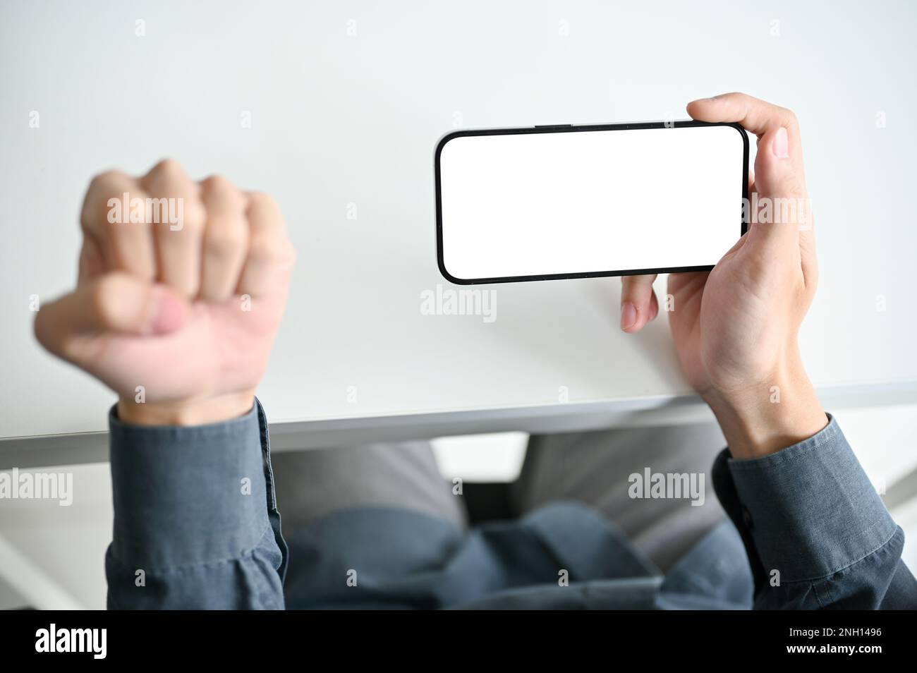 Top view of a man holding a smartphone white screen mockup over the ...