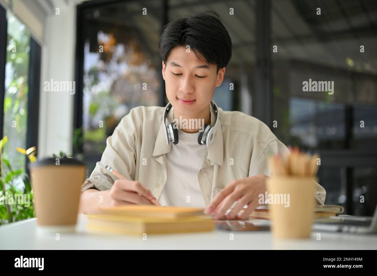 Smart and focused young Asian male college student is in the coffee ...