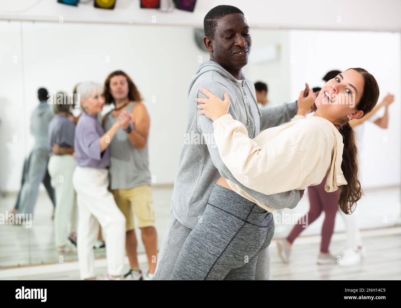 Dancing positive couples learning salsa Stock Photo - Alamy