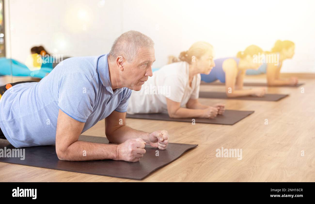 Old man practicing pilates on mat in gym area Stock Photo - Alamy