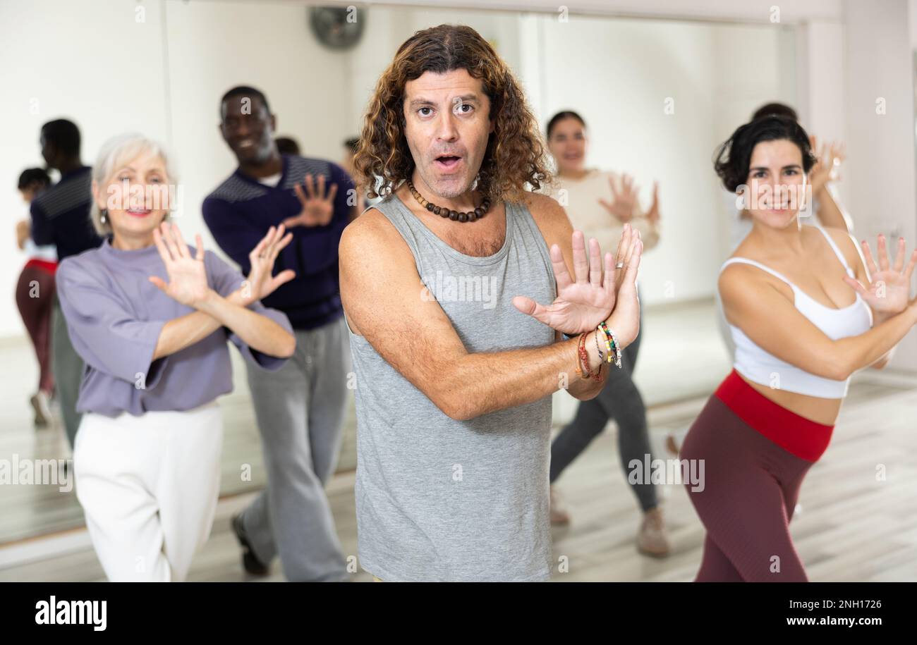 Positive man practicing vigorous dance movements during group class ...