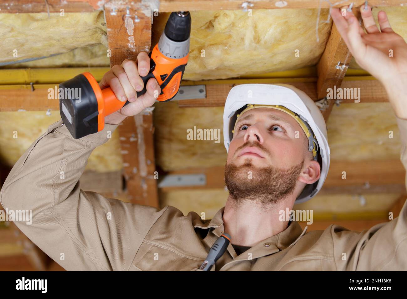 handsome builder working on ceiling Stock Photo - Alamy