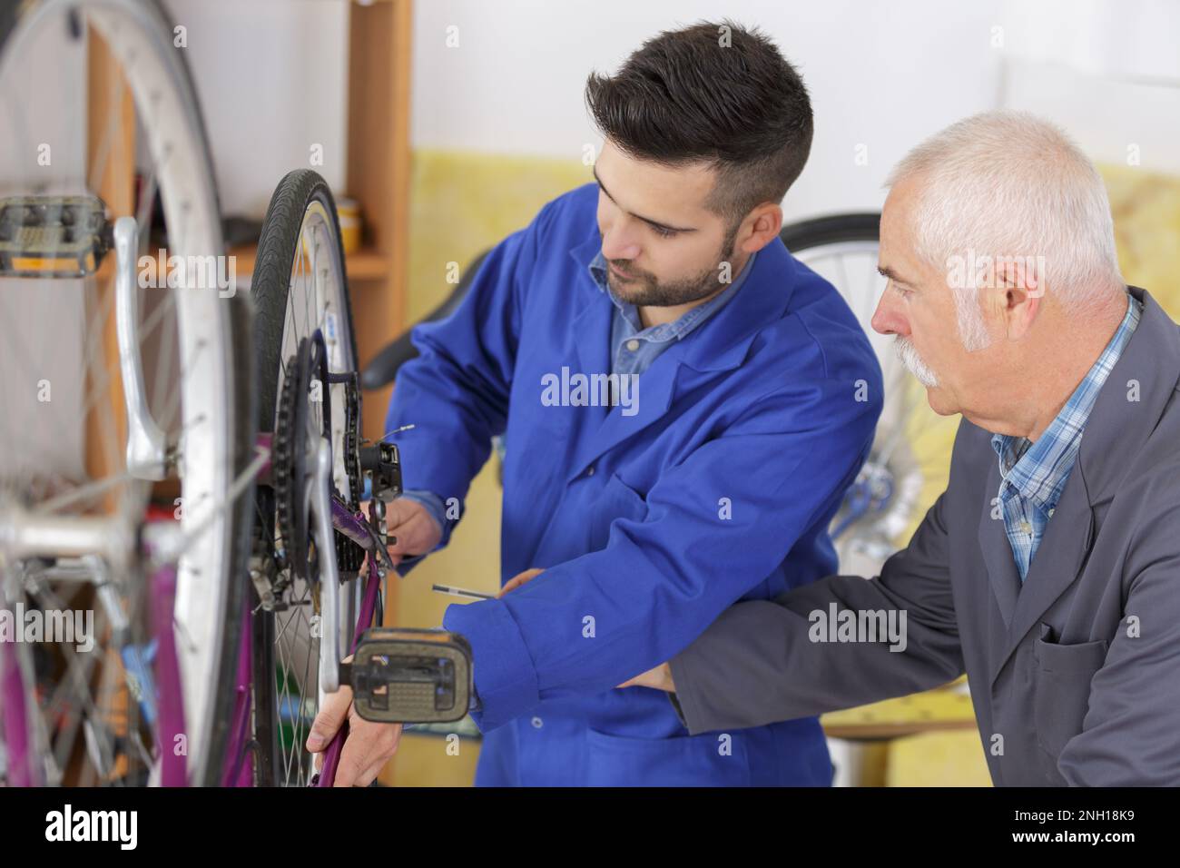 two mechanics fixing bicycles wheel in a workshop Stock Photo - Alamy