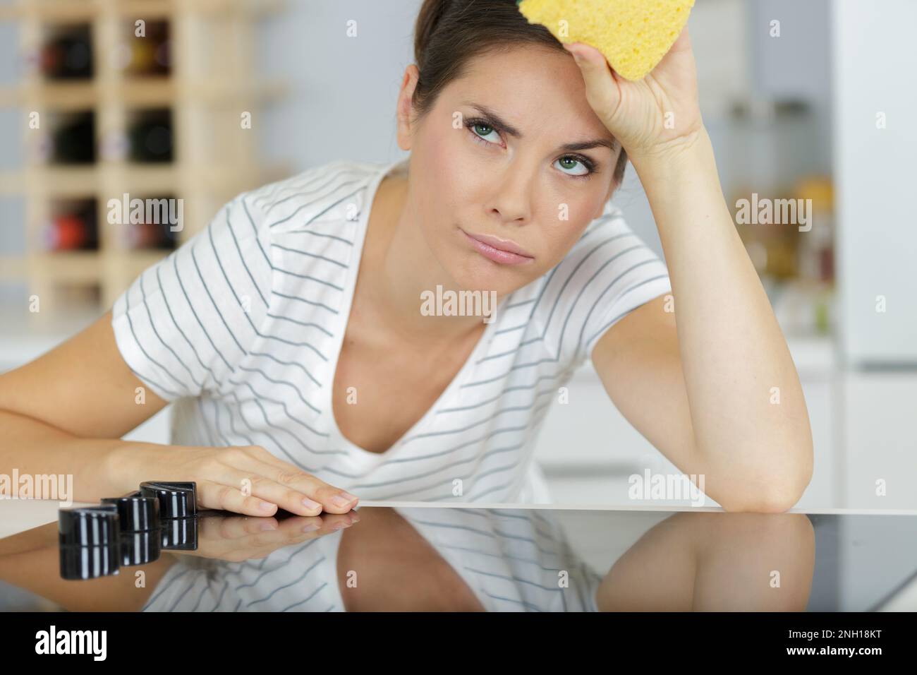 tired woman cleaning kitchen with big sponge Stock Photo - Alamy