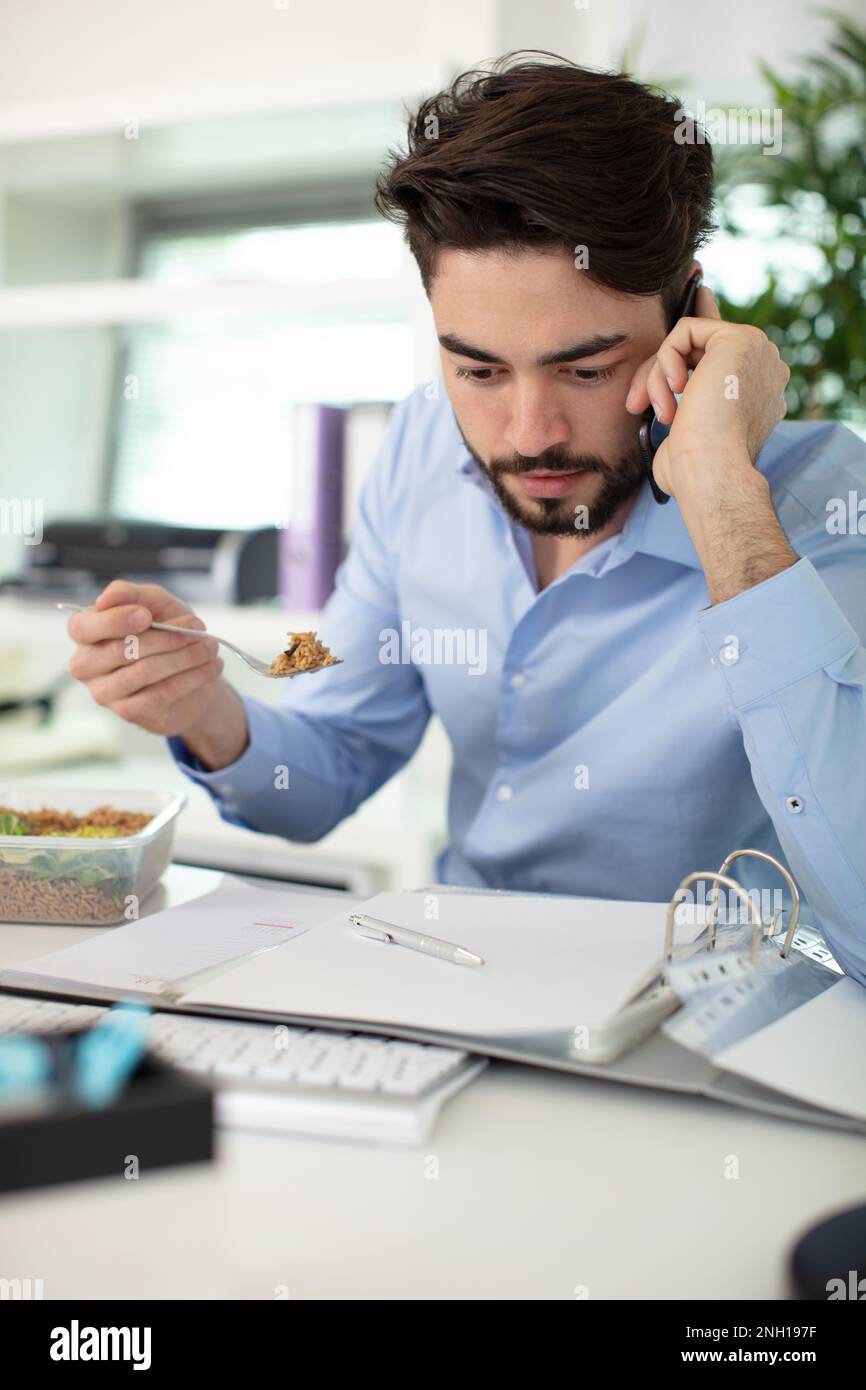 professional man working through lunch eating packaged food Stock Photo ...