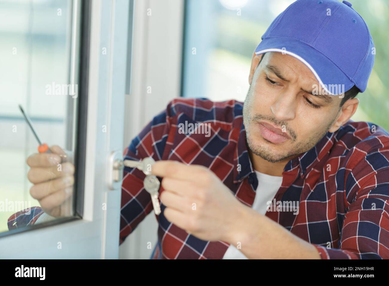 a carpenter install door lock with wireless screwdriver Stock Photo - Alamy