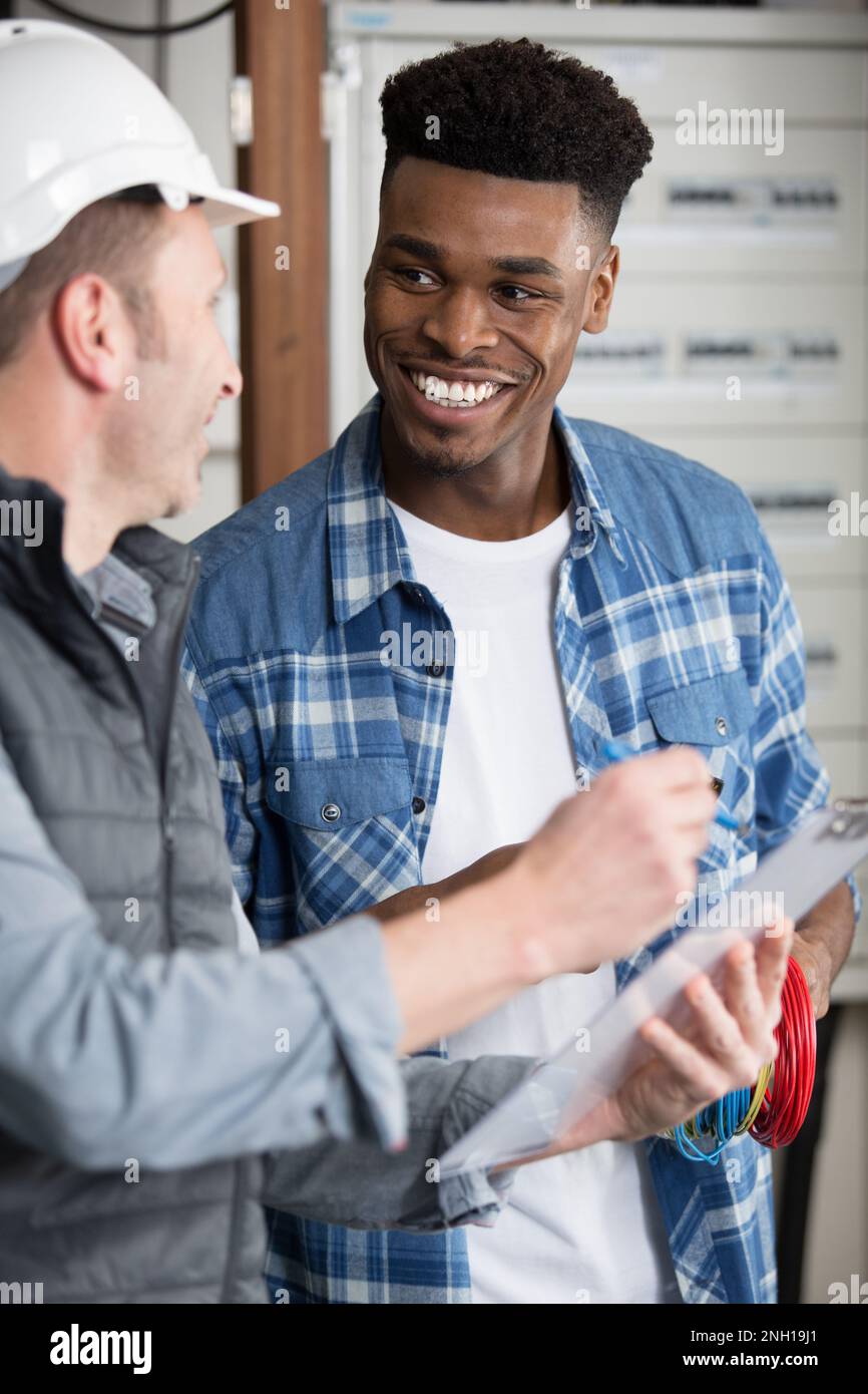 electrician with clipboard talking to his assistant Stock Photo - Alamy