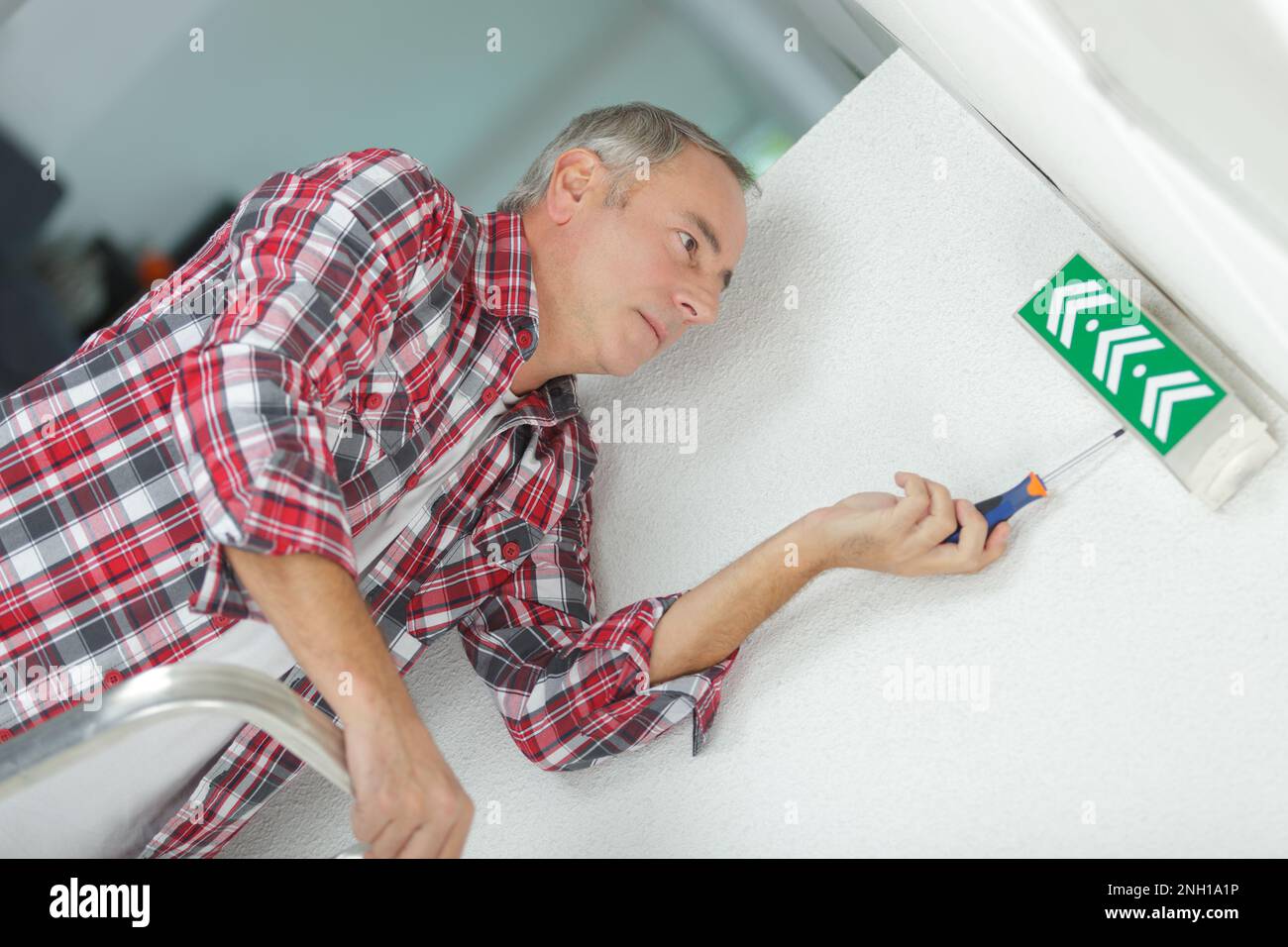 man fixing illuminated exit sign to wall Stock Photo - Alamy