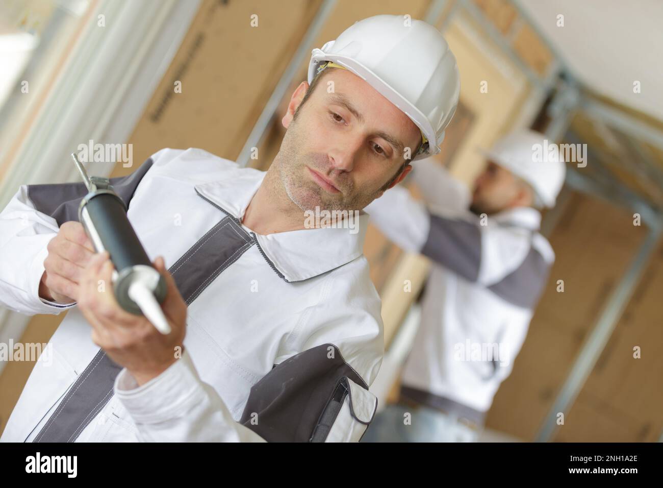 builder using a silicone tube for repairing the window indoor Stock ...