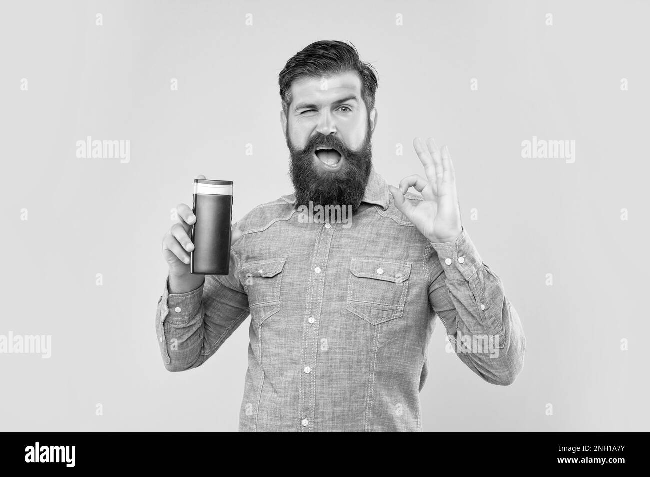 Winking Brutal Bearded Man Hold Shampoo Bottle On Yellow Background