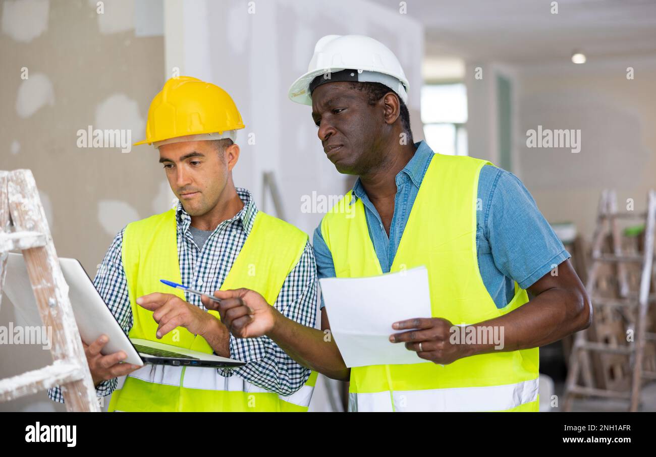 Two engineers discussing blueprints in renovated room Stock Photo - Alamy