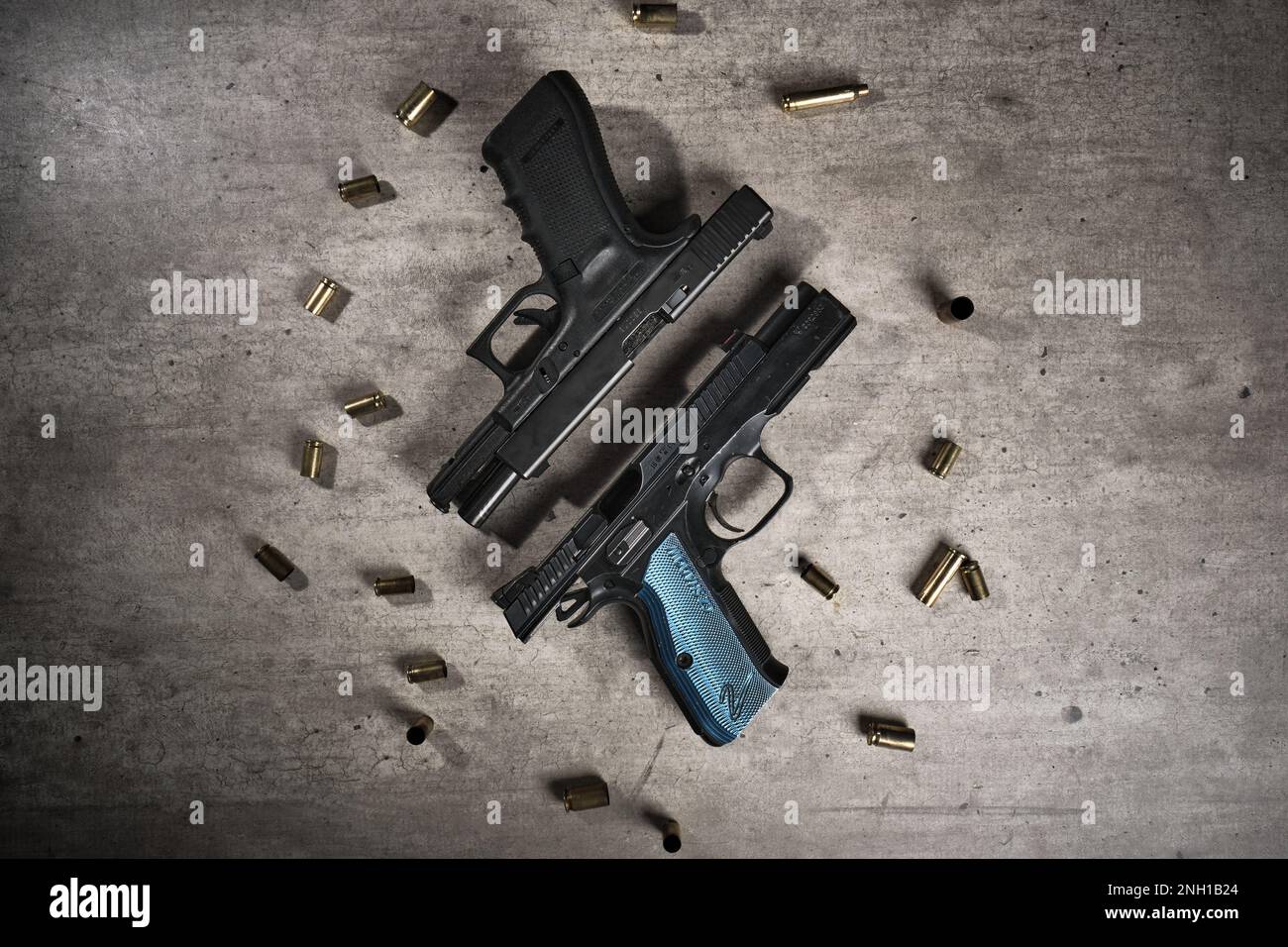 two handguns laid down opposite to each other with bullets around them ...