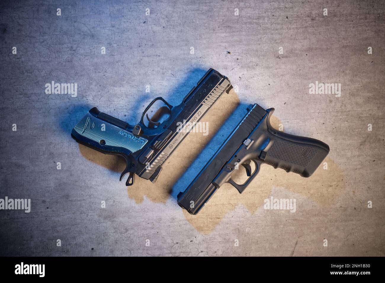 two handguns laid down opposite to each other on a wooden background ...