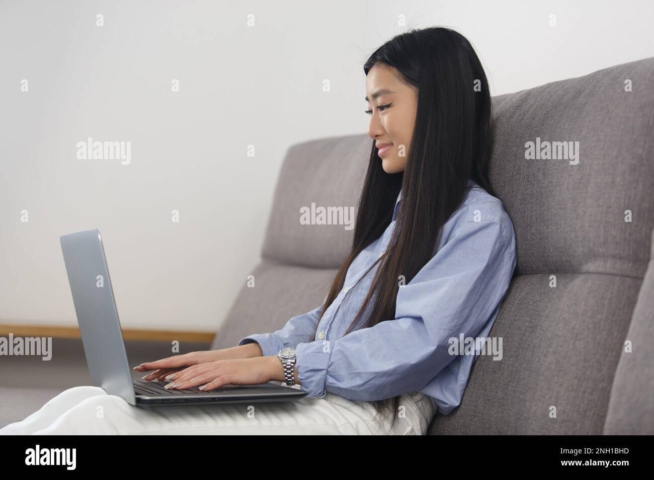 Beautiful young Vietnamese girl working on computer at home. Cheerufl ...