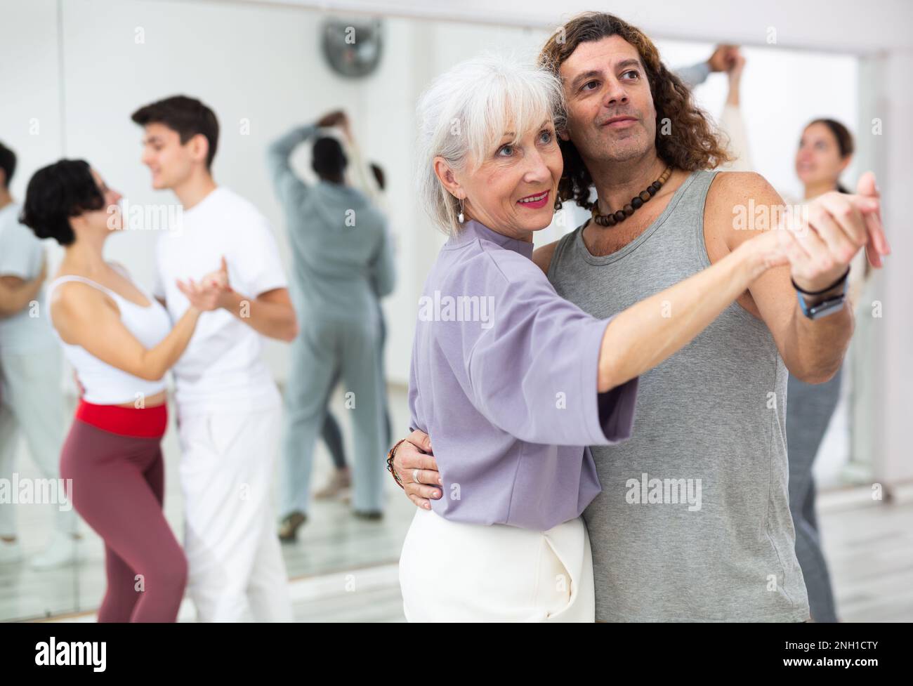 Positive adult man and smiling aged woman dancing in pair Stock Photo ...