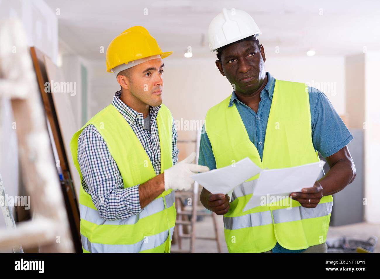 Two engineers discussing blueprints in renovated room Stock Photo - Alamy