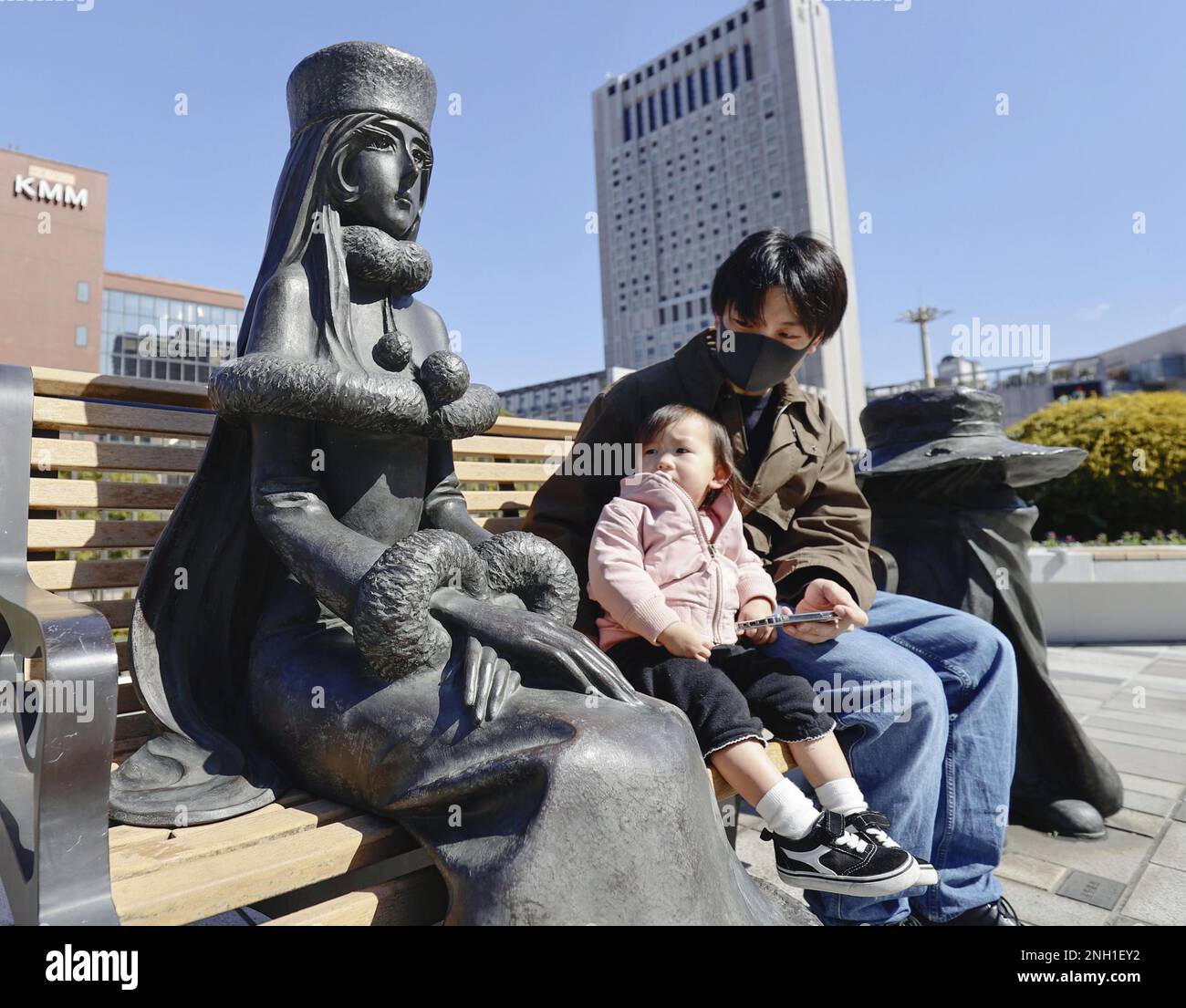 A man and a child sit near a statue of Maetel, a lead character in ...