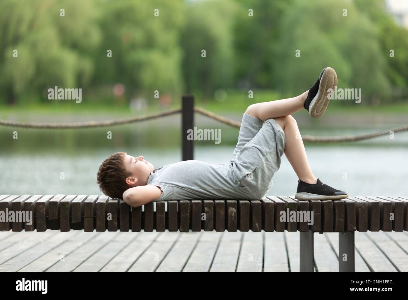 A school-age boy is lying on a bench in the park Stock Photo - Alamy