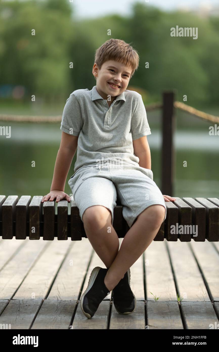 The boy is sitting on a bench and smiling Stock Photo - Alamy