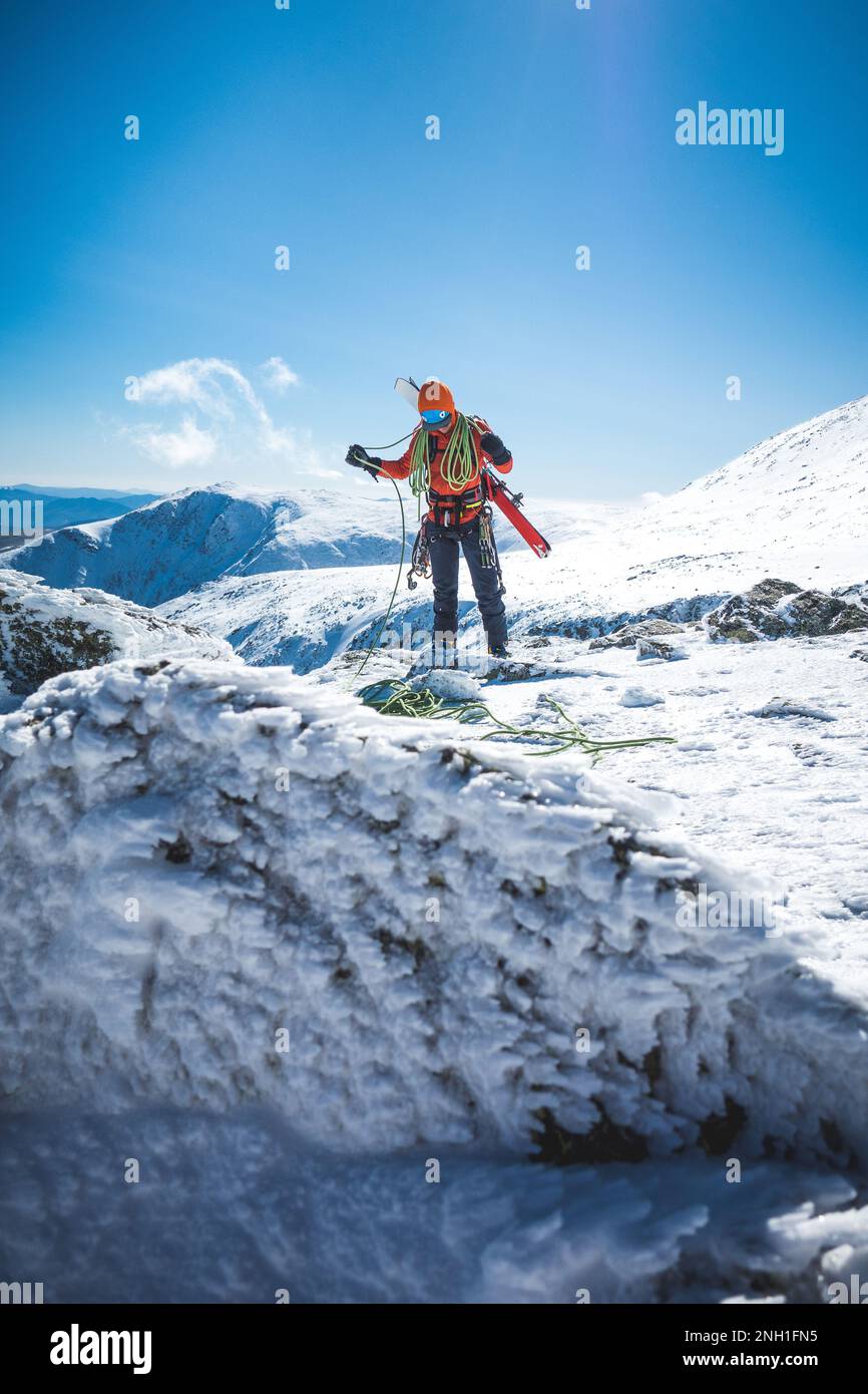 Ski mountaineer coiling rope with snowy mountains behind Stock Photo ...