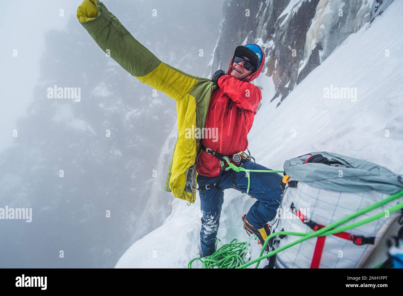 Ice climber putting on heavy jacket while on a climb Stock Photo - Alamy