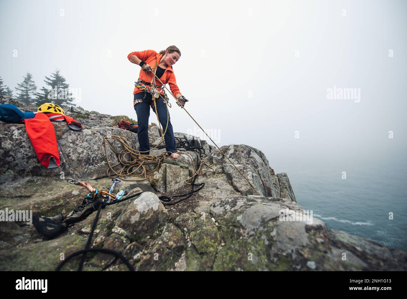 Woman pulling up rope after climbing on seaside cliff Stock Photo - Alamy