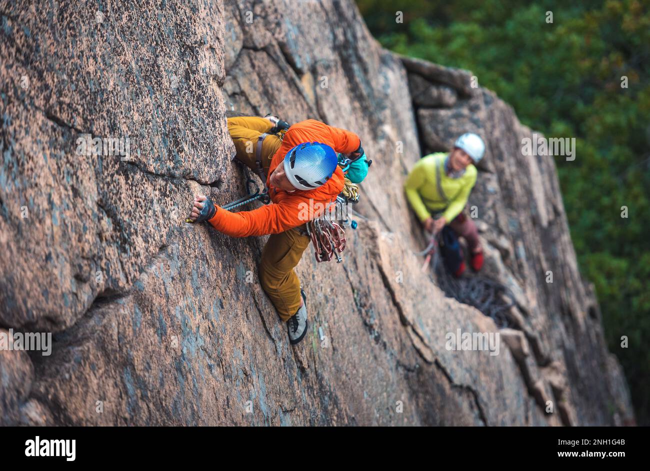 Man rock climbing on rock face with belayer below Stock Photo - Alamy