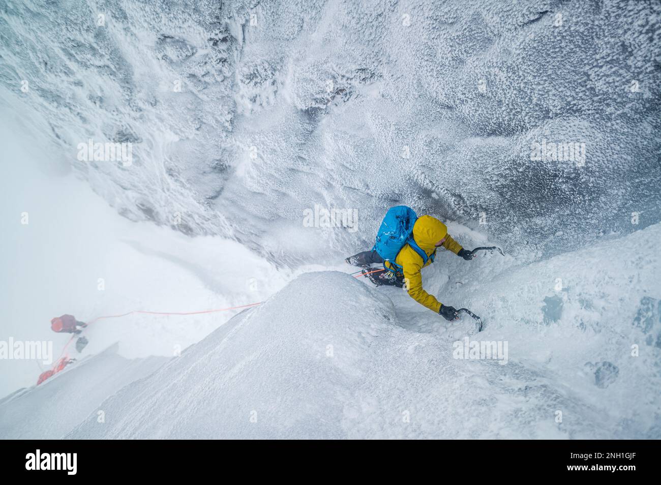 Male mountaineer climbing technical ice gully in cold temperatures ...