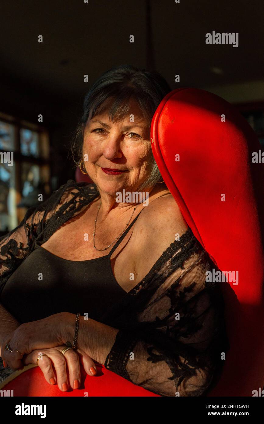 Confident woman in red chair Stock Photo - Alamy