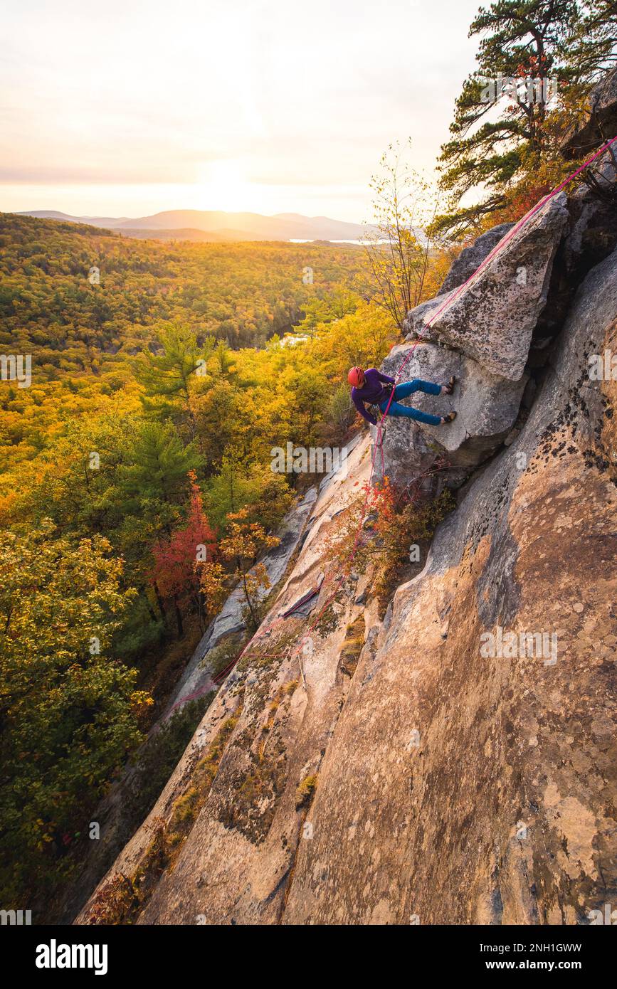 Rock climber rappelling with mountains and foliage in background Stock ...