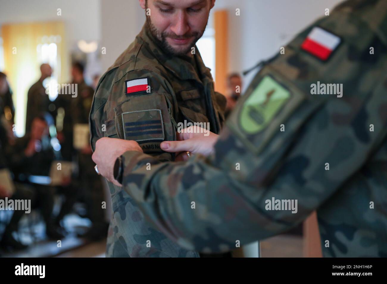 A Polish soldier is awarded an Abrams number 1 patch signifying ...